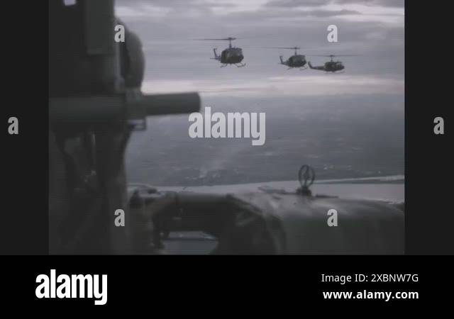 1960s, 1970s - A fleet of UH-1D helicopters fly high above the fields ...