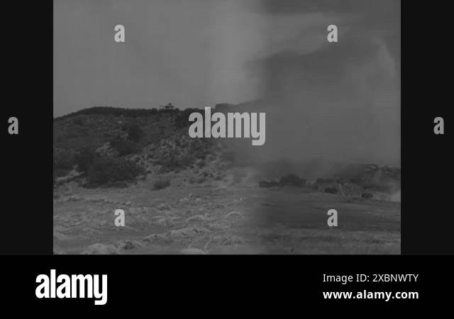 1943 - Tanks move through hilly terrain and dust clouds are formed and ...