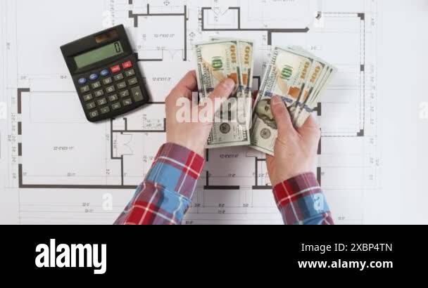 Designer counts cash money and marks total on calculator over floor ...