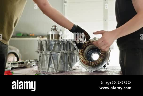 Two mechanics working on disassembling and repairing an electric car ...