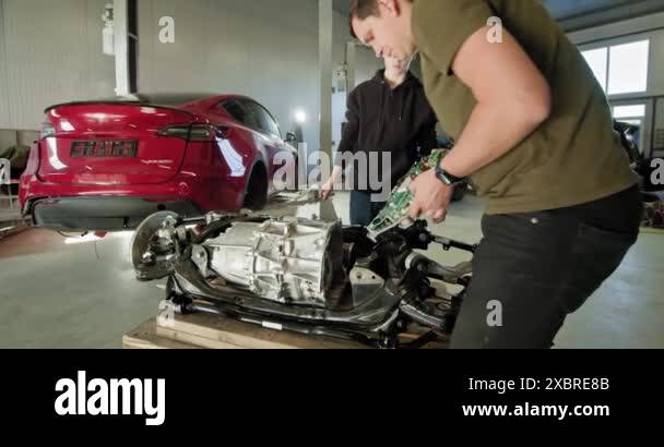 Car mechanics working on disassembled electric vehicle engine in an ...