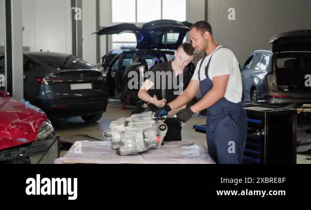 Mechanics Repairing Electric Car Engine. Two mechanics working on a ...