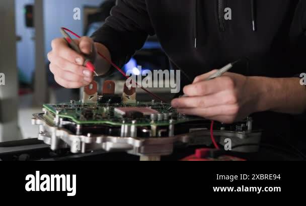 Mechanic uses tools to perform maintenance on a disassembled electric ...