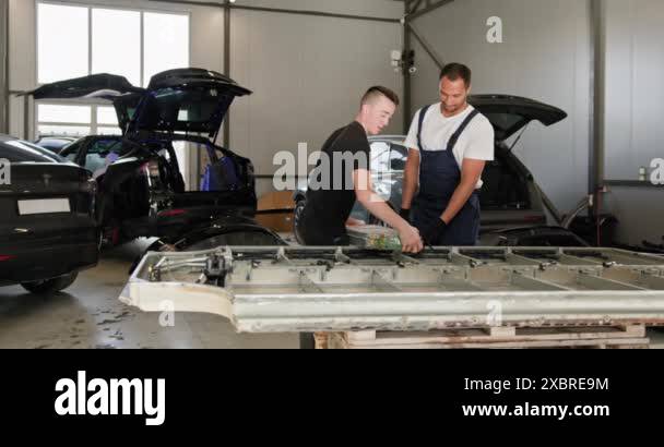Two Male Technicians Repairing And Troubleshooting An Electric Car ...
