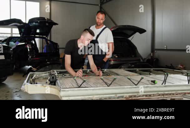 Two Technicians Repairing An Electric Car Battery Module In A Workshop ...