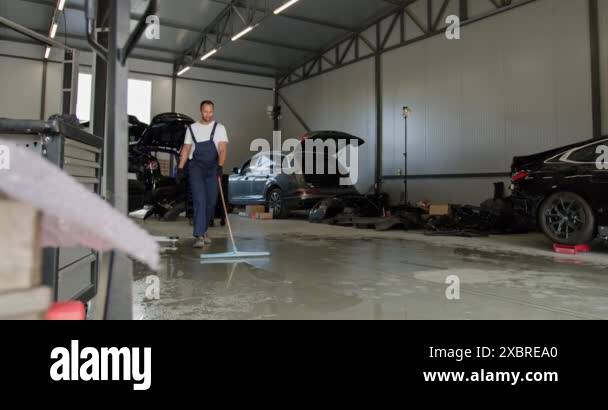 Mechanic Cleaning Auto Workshop Floor. Mechanic Mopping The Floor Of An ...