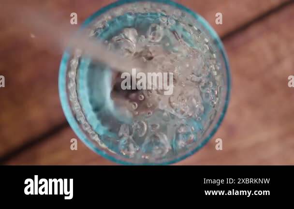 A high angle shot captures water falling into an already full glass ...
