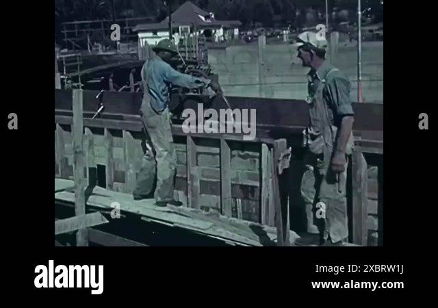 Concrete workers pour a transit mix into wooden forms and curbs and ...