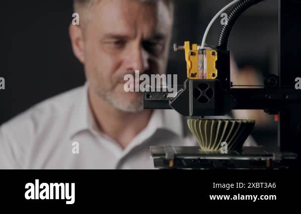 A middle aged man graphic designer observes the working process of 3d ...