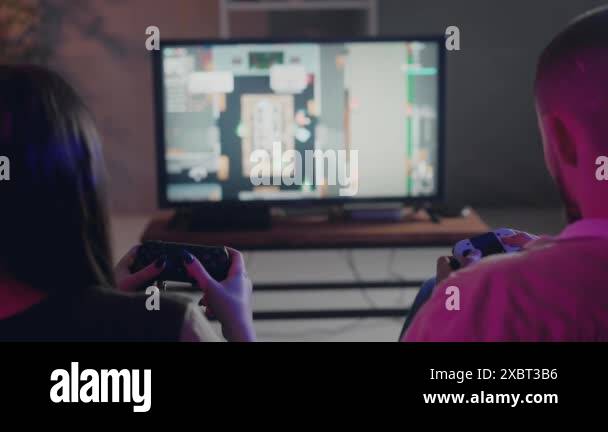 Brother and sister play nostalgic vintage arcade game. Rear shot of two ...