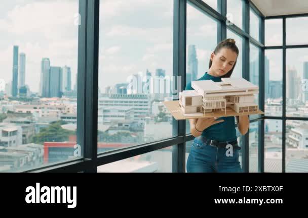 Young happy beautiful engineer check house model by turning left side ...