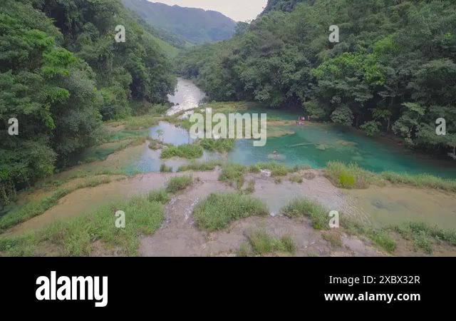 An aerial over remarkable waterfalls and green polls on the Semuc ...