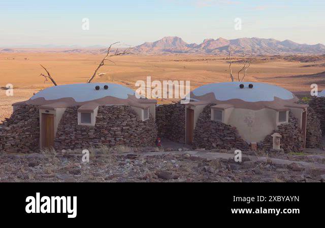 Stone huts of a remote lodge in the Namib Desert overlook a vast desert ...