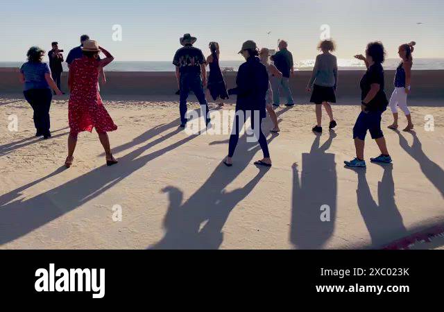 People practice learn line dancing and dance outdoors at a beach in ...