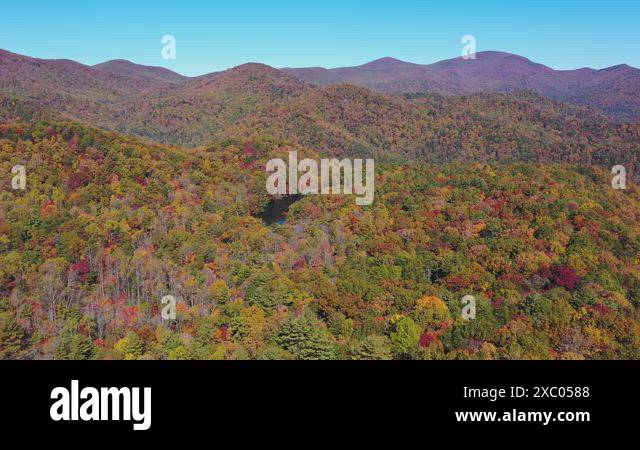 Beautiful aerial of mountain lake and trees turning color in autumn or ...