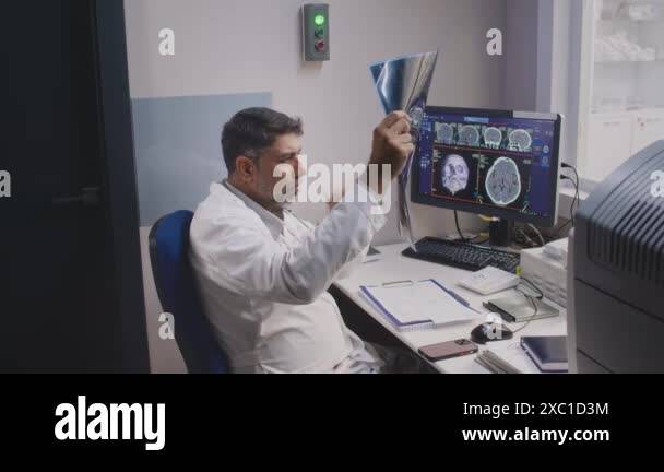 Medium shot of mature male radiologist wearing white lab coat and ...