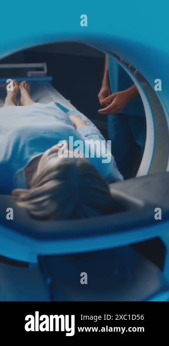 Inside vertical view of MRI capsule with woman in hospital gown lying ...