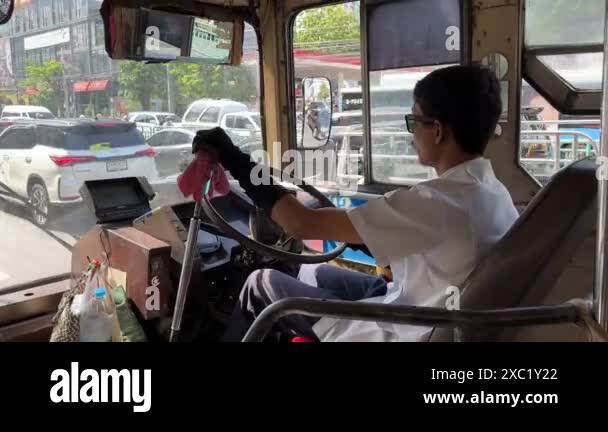 The bus driver is shifting gears and turning the big steering wheel in ...