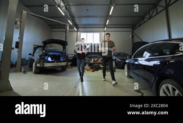 Two mechanics working on repairing electric vehicles in a modern auto ...