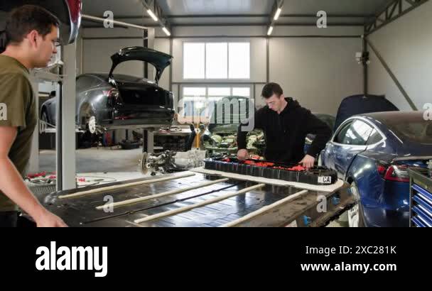 Two technicians assembling a high-voltage lithium-ion battery pack for ...