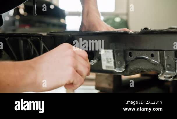 Close-up of a mechanics hands repairing an electric vehicle battery ...