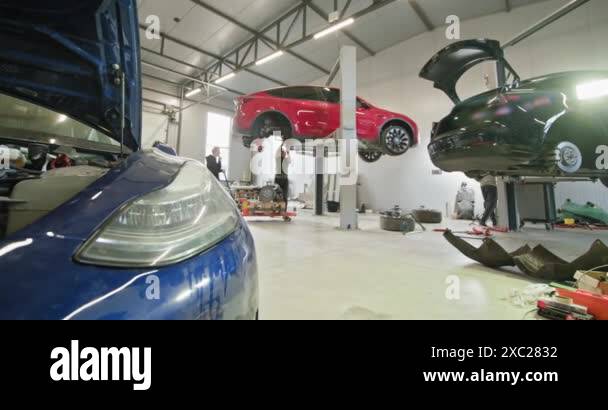 Mechanics performing maintenance and repairs on electric vehicles in a ...