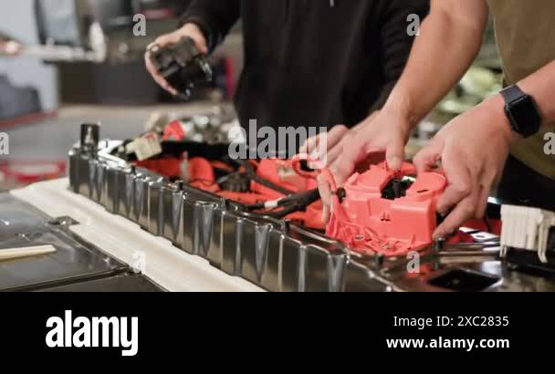 Two technicians are working on an electric car battery pack in a ...