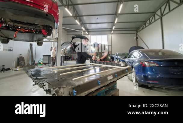Two technicians working on repairing a lithium-ion battery pack for an ...