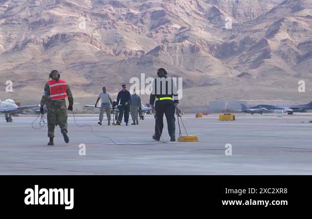 Maintenance workers on an air force runway with F-15 and F-16 jet ...