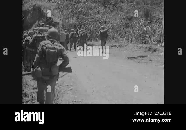 1945 - American soldiers follow armored vehicles along a jungle road in ...