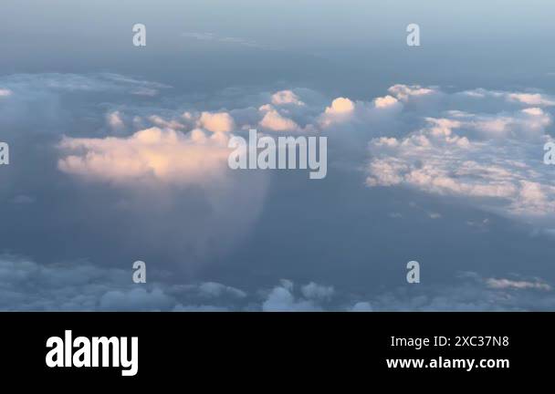 Observing the cumulus clouds in the atmospheric landscape from an airplane window at sunset ...
