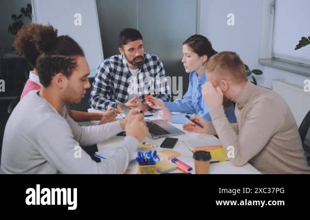 Team members engage in heated discussion to develop a consensus during an office meeting ...