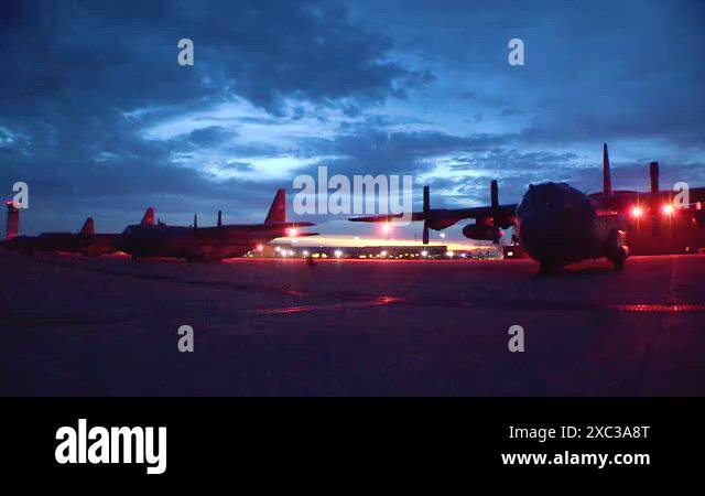 A fleet of C-130 Herculese sit on the flightline during sunrise in this ...