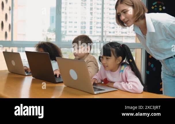 Smart teacher teaching and looking student using laptop at classroom ...