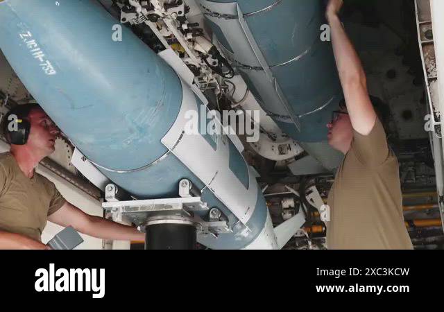 Missiles are loaded onto an aircraft by members of the A4 Air Force ...
