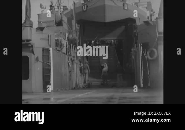 1944 - US Army trucks are driven down the ramps of an LST for D-Day ...