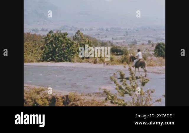 MEXICO - 1965 - A boy on his donkey rides past people doing chores and ...