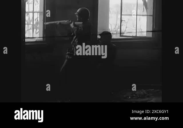 1945 - Infantrymen fire guns out a window from inside a building on a ...