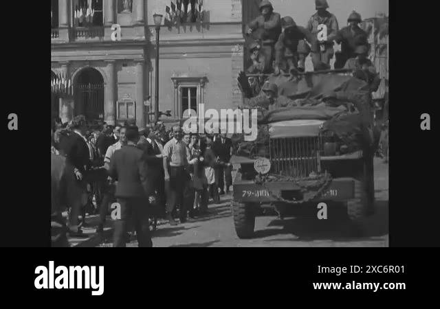 1944 - American soldiers, standing on tank, throw candy and cigars to ...