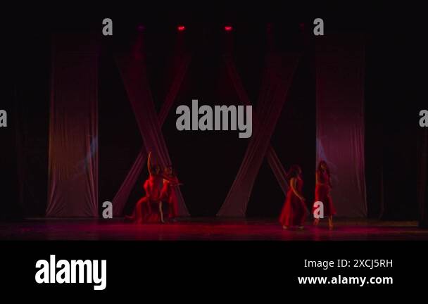 Silhouetted dancers on stage with dramatic red lighting and shadows ...