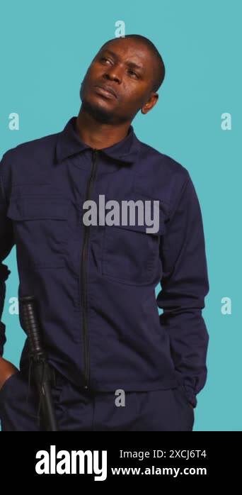 Vertical video Portrait of security guard scratching head with baton ...