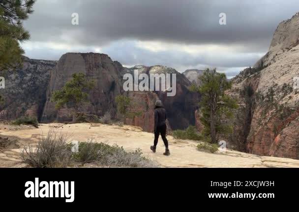 A female hiker walks towards the edge of a cliff above Angels Landing ...