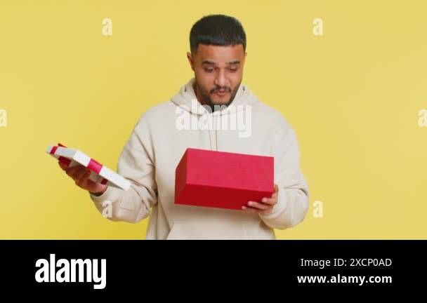 Happy Indian young man opening birthday gift box with red ribbon ...