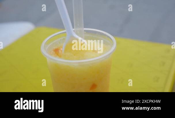 Fortified freshly squeezed orange and mango juice with crushed ice, in ...