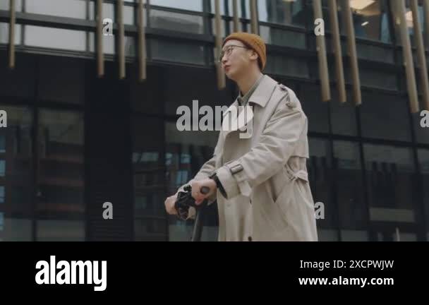 Tracking side view medium shot of Asian young man wearing trench coat ...