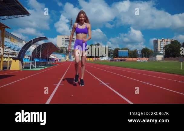 Young woman sprinting on track at the stadium. Female athlete running on track. Beautiful woman ...