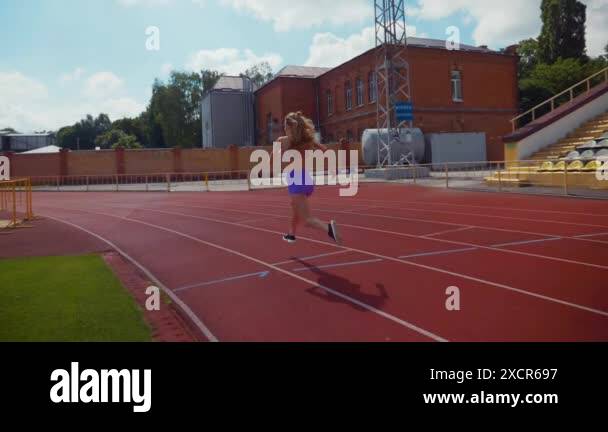 Young woman sprinting on track at the stadium. Female athlete running ...