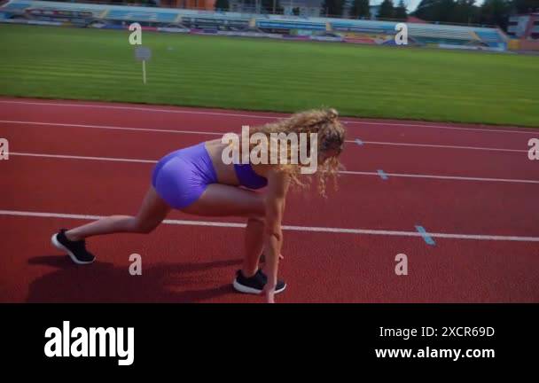 Young woman sprinting on track at the stadium. Female athlete running ...