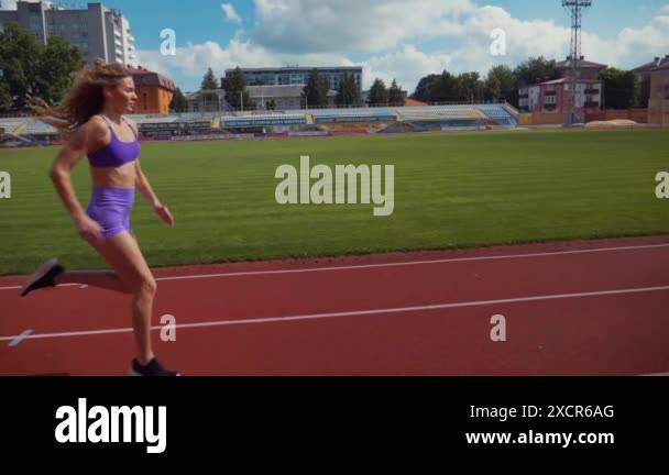Young woman sprinting on track at the stadium. Female athlete running on track. Beautiful woman ...
