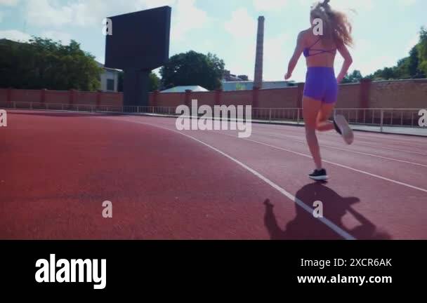 Young woman sprinting on track at the stadium. Female athlete running on track. Beautiful woman ...